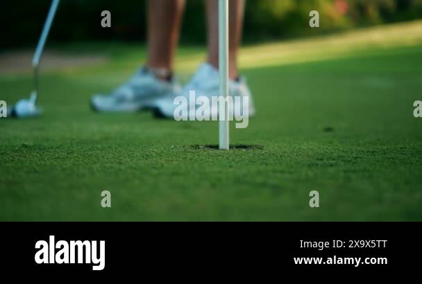 Close-up of the legs of a young woman playing golf on the green lawn of ...