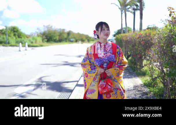 A young woman in her twenties, wearing traditional Ryusou, is walking ...