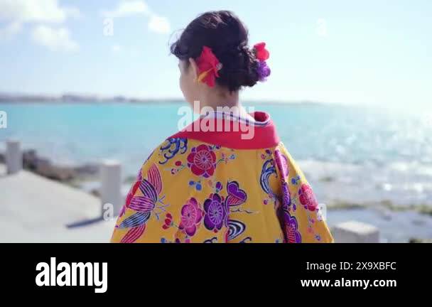 A young woman in her twenties, wearing traditional Ryusou, walks along ...
