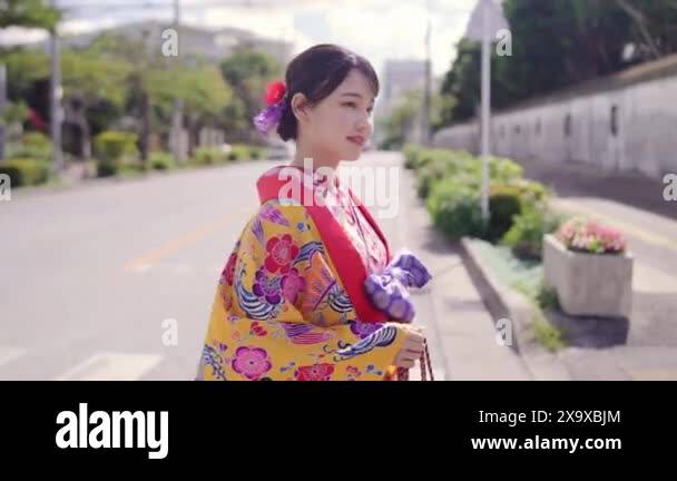 A young woman in her twenties, wearing traditional Ryusou, walks down a ...
