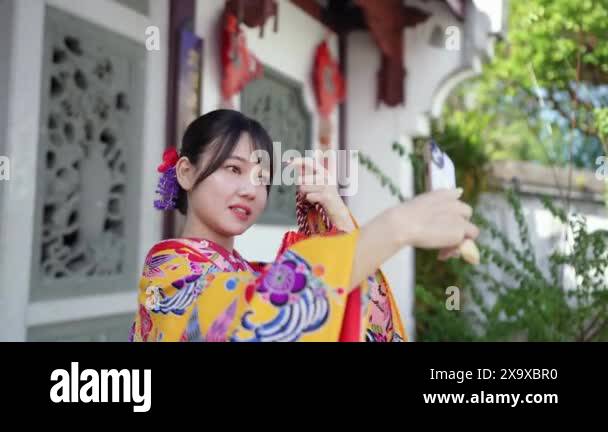 A young woman in her twenties, wearing traditional Ryusou, takes a ...