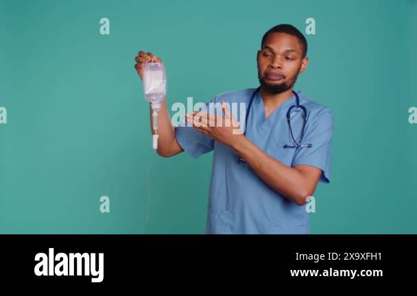 Male nurse holding IV bag, preparing to use it to administer fluids ...