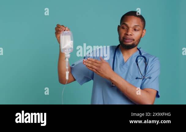 Male nurse holding IV bag, preparing to use it to administer fluids ...