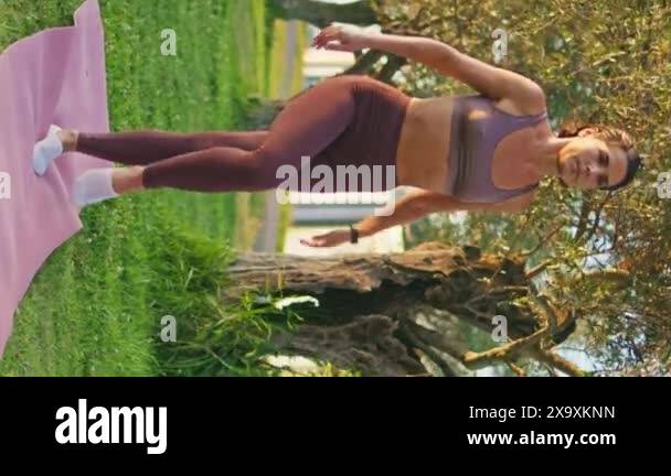 Yoga model practicing asana at sunny park vertical. Mature woman ...