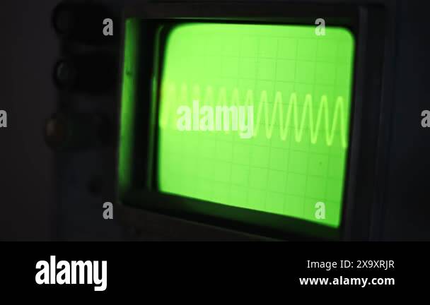 A vintage oscilloscopes CRT displays a green signal moving across a ...