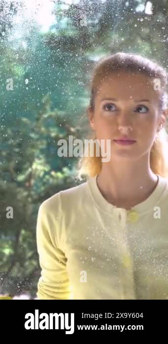 Young attractive woman cleaning a window with a special detergent spray ...