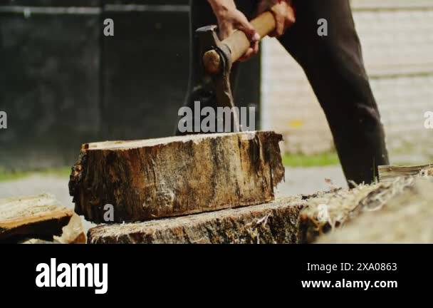 Person chopping wood with an axe on a tree stump, with sawdust flying ...
