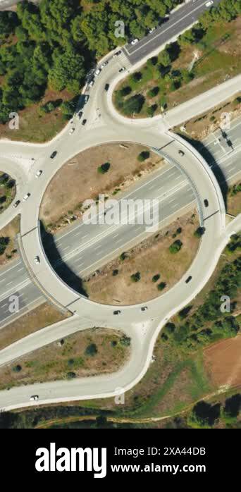Vertical video of a circular highway intersection surrounded by ...