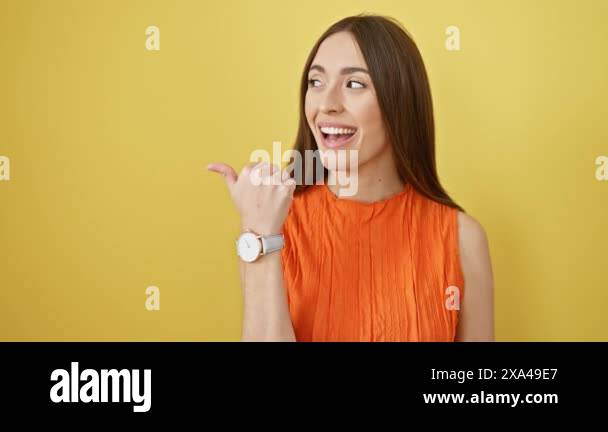 Cheerful latina in sleeveless tee pointing sideways, showing her thumb ...