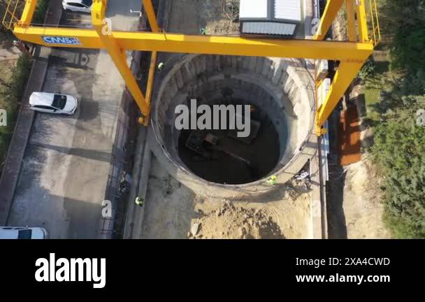 Construction equipment fills a bucket with excavation inside a deep ...