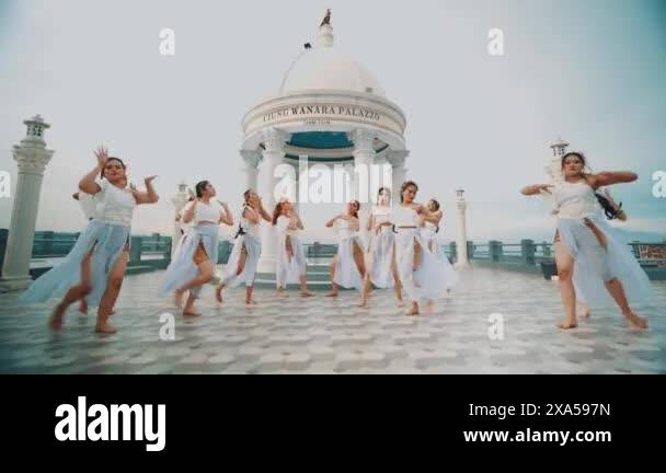 A group of women dressed in white performing a traditional dance in ...