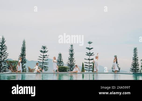 A group of people dressed in white performing synchronized dance poses ...