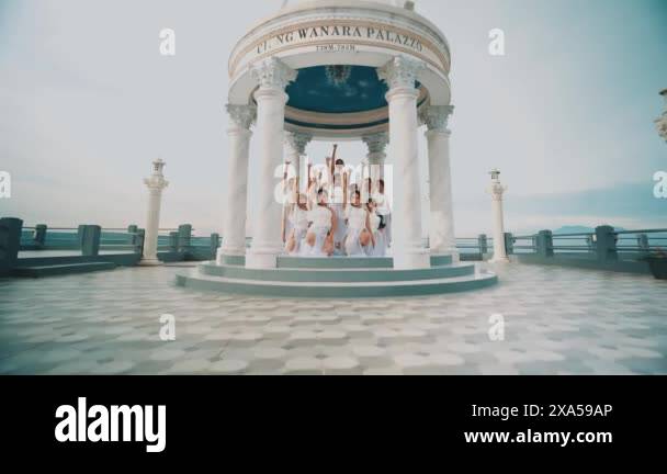 A group of dancers in white costumes performing a synchronized dance ...
