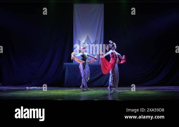 Two dancers performing a traditional dance on a dimly lit stage with a ...