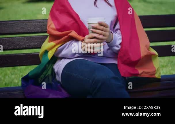 In the park lgbt lady on a chair sitting down and drinking something ...