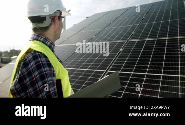 Technician inspect Solar cell Farm through field of solar panels checking the panels at solar ...