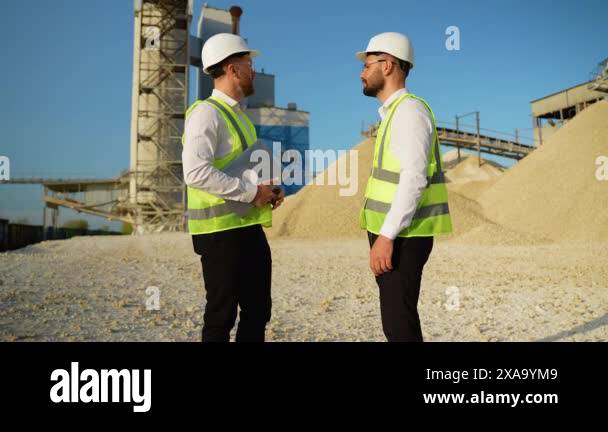Two men engineers are talking and shaking hands at quarry. Team of male ...