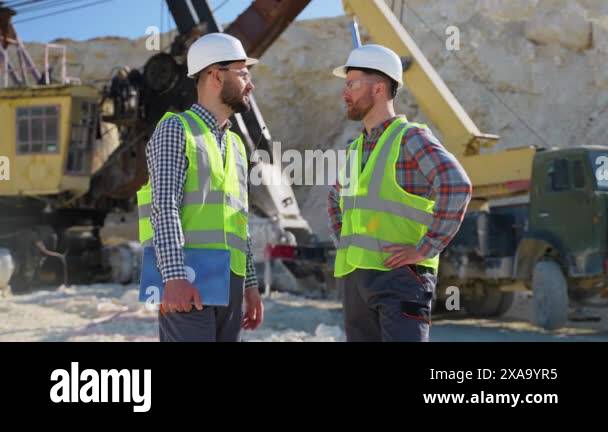 Two men engineers in uniform are talking at the stone quarry. Team of ...
