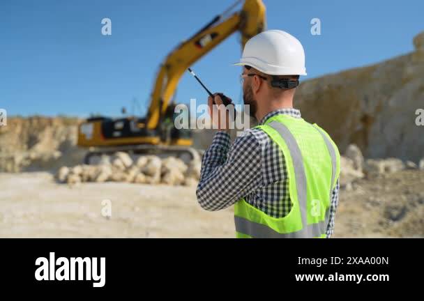 Foreman in uniform giving commands to employee in excavator using ...