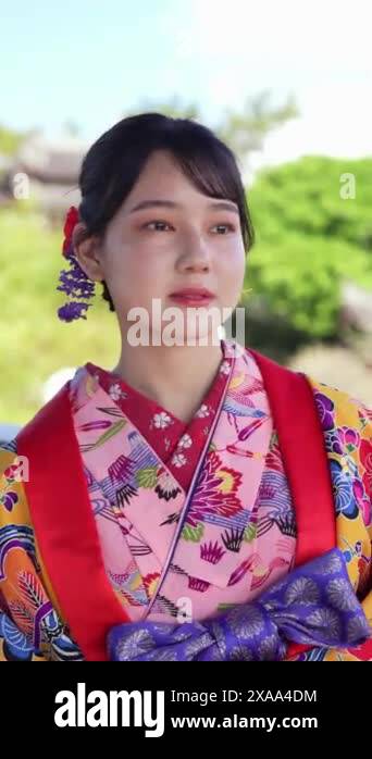 A young woman in her twenties, wearing traditional Ryusou, sits and ...