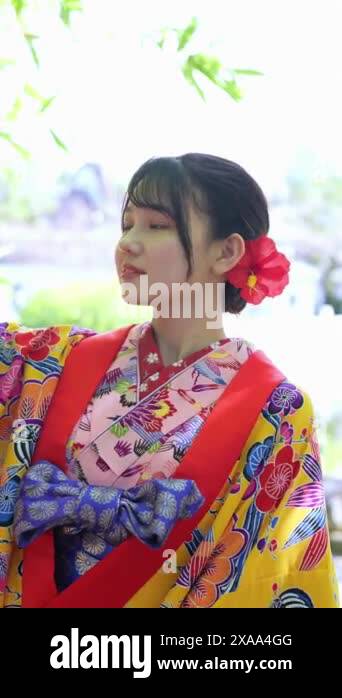A young woman in traditional Ryuso attire captures a selfie in a ...