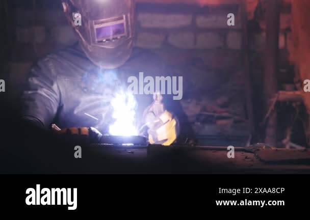 A metal welder works with an arc welder to weld steel at home, using ...