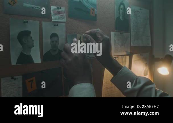 Close-up zoom out shot of African American detective pinning murder ...