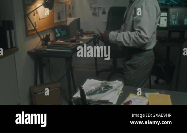 Medium tracking shot of African American police detective picking up ...