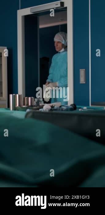 Two professional surgeons in uniforms, gloves, masks and hats enter the ...