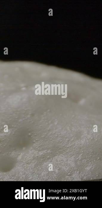 Camera zooming out from soft white foam bubbling and fizzling on top of ...