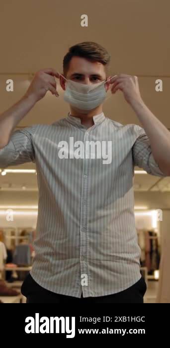 A young man puts a mask on his face in a clothing store. Portrait of ...