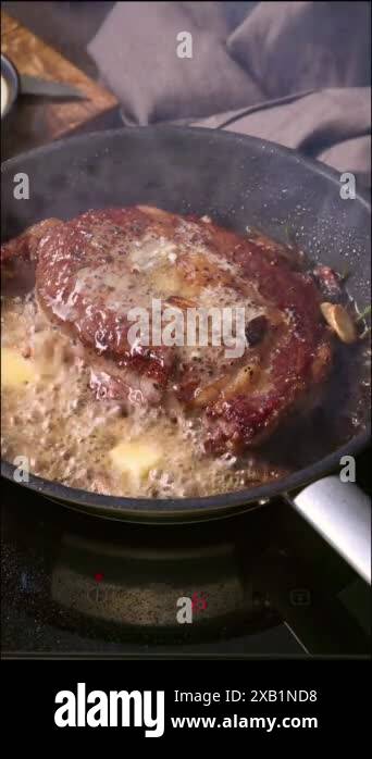 A chef cooks a beef steak on a pan in the kitchen and turns it to the ...