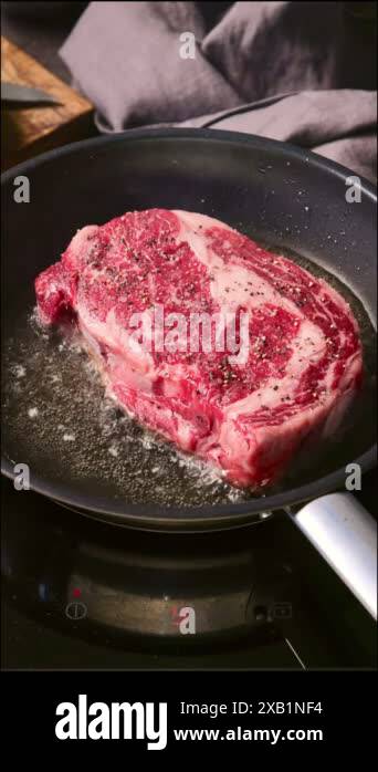 A chef cooks a beef steak on a pan in the kitchen, food close-up ...