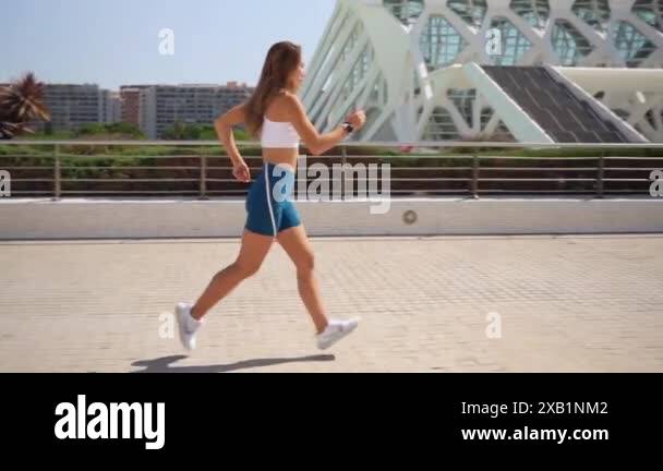 Asian oriental adult woman jogger in sportswear running workout sunny morning urban high tech ...