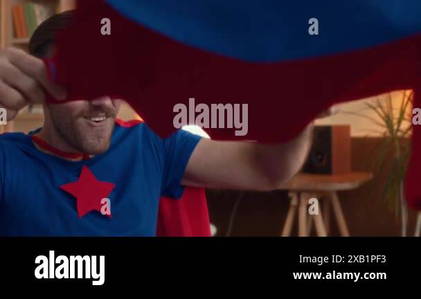 Excited young Caucasian man dressed up like superhero waving red and ...