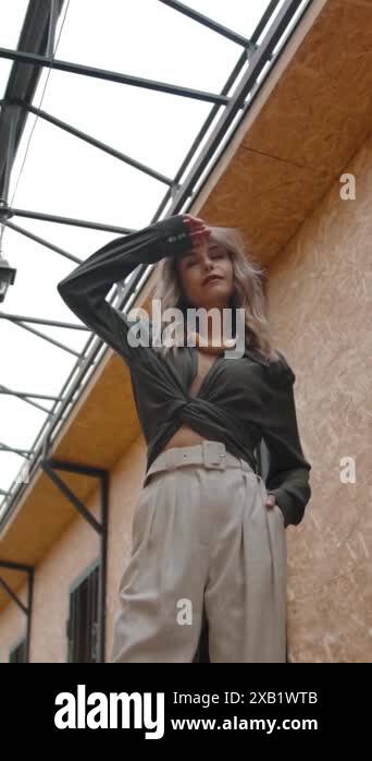 Low angle of elegant lady putting hand on head and whirling while ...