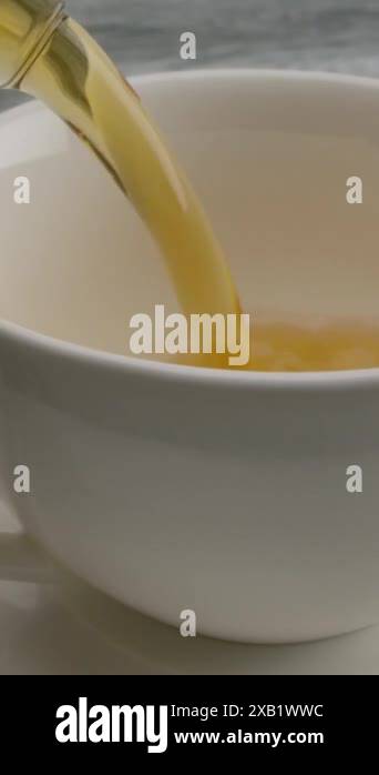 Pouring black tea into a classic white cup on a saucer from teapot ...