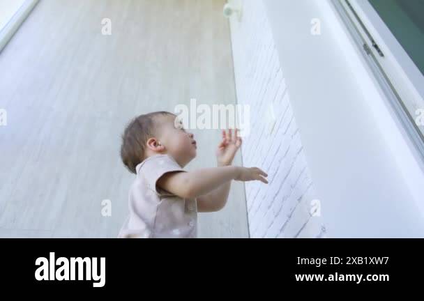 Little kid wants to reach the lamp on the wall. Funny kid gestures ...
