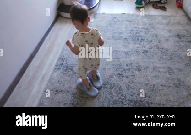 Following funny little boy wearing big slippers. Kid comes up to stairs ...