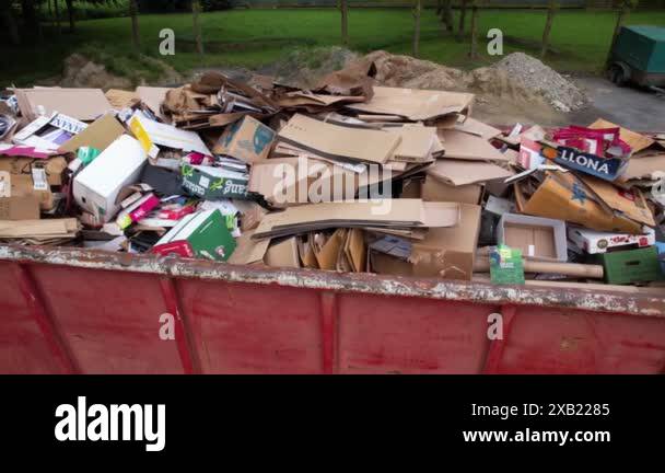 A full recycling container overflowing with cardboard boxes. This ...