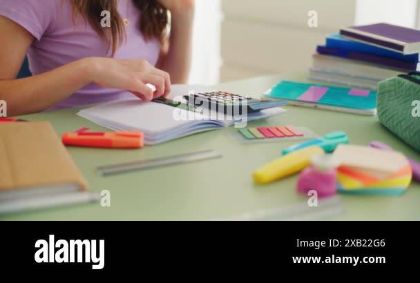 Young schoolgirl uses a calculator to count and study while doing her ...
