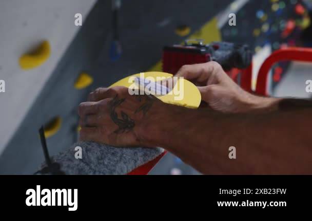 A close-up shot of hands installing a yellow climbing hold on an indoor ...