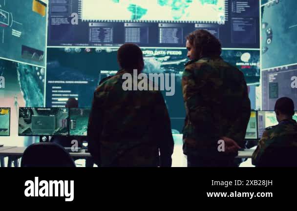 Military surveillance officers talking next to a big screen in general ...