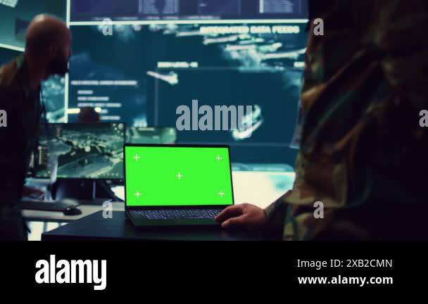 Army officer studies isolated greenscreen display on a laptop in ...