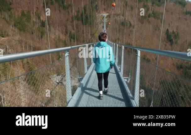 Female traveller walking on suspension bridge in tourist destination ...