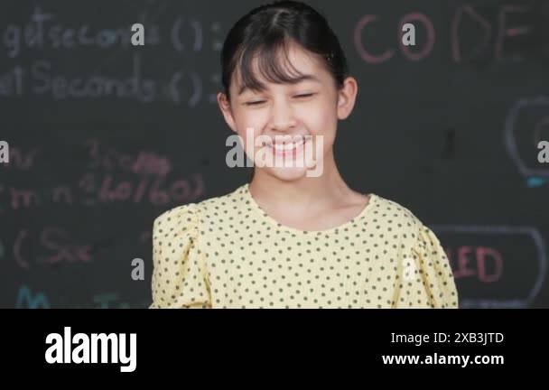 Cute happy girl smiling to camera while standing at blackboard with ...