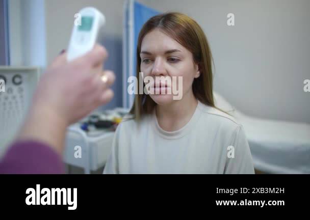 Close-up. Female doctor brings a non-contact infrared thermometer to ...