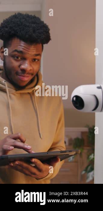 African American man installs security camera. Man sets up angle of ...