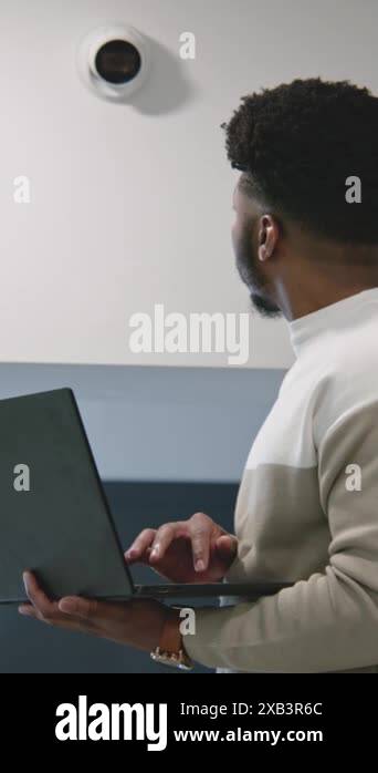 African American installer sets up security camera in office room using ...