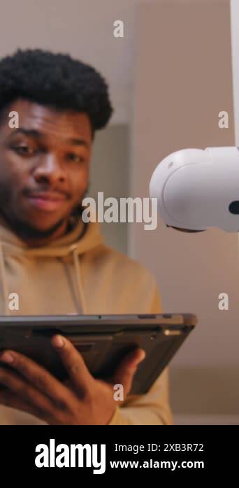 African American man installs security camera. Man sets up angle of ...